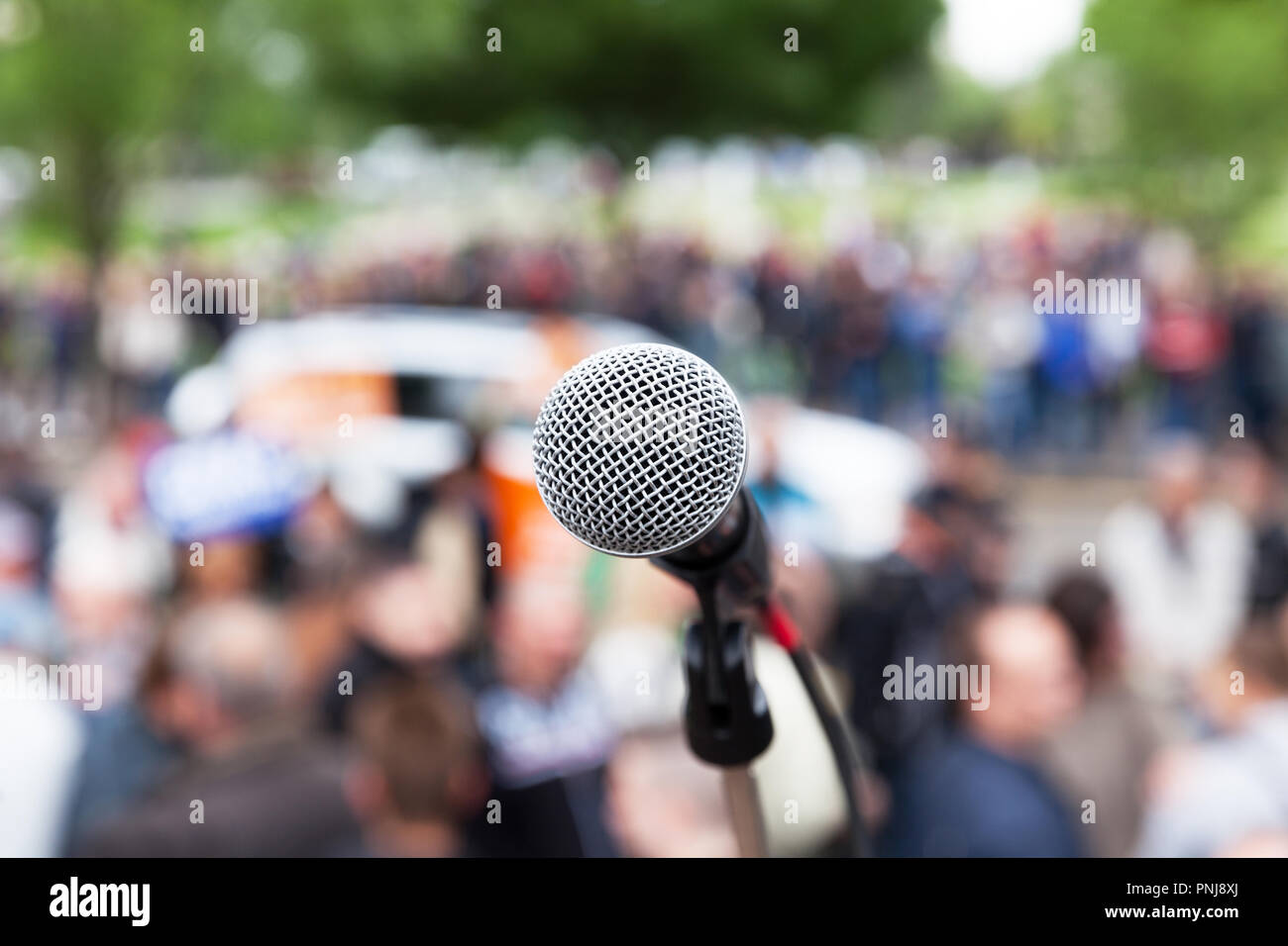 Microphone in focus, blurred crowd in the background. A political rally ...