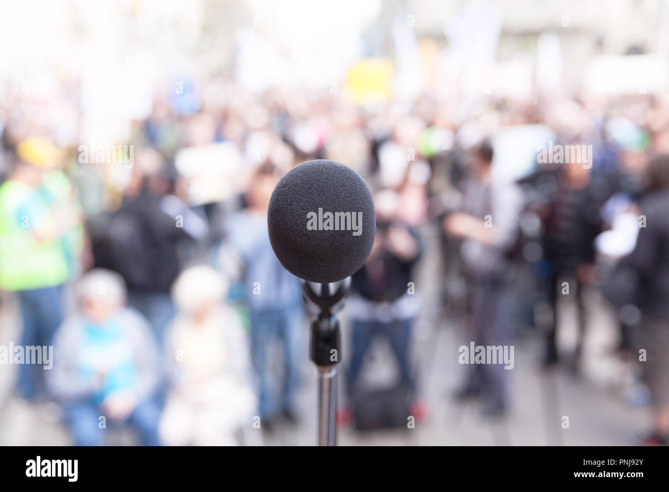 Microphone in focus, blurred crowd in the background. A political rally ...