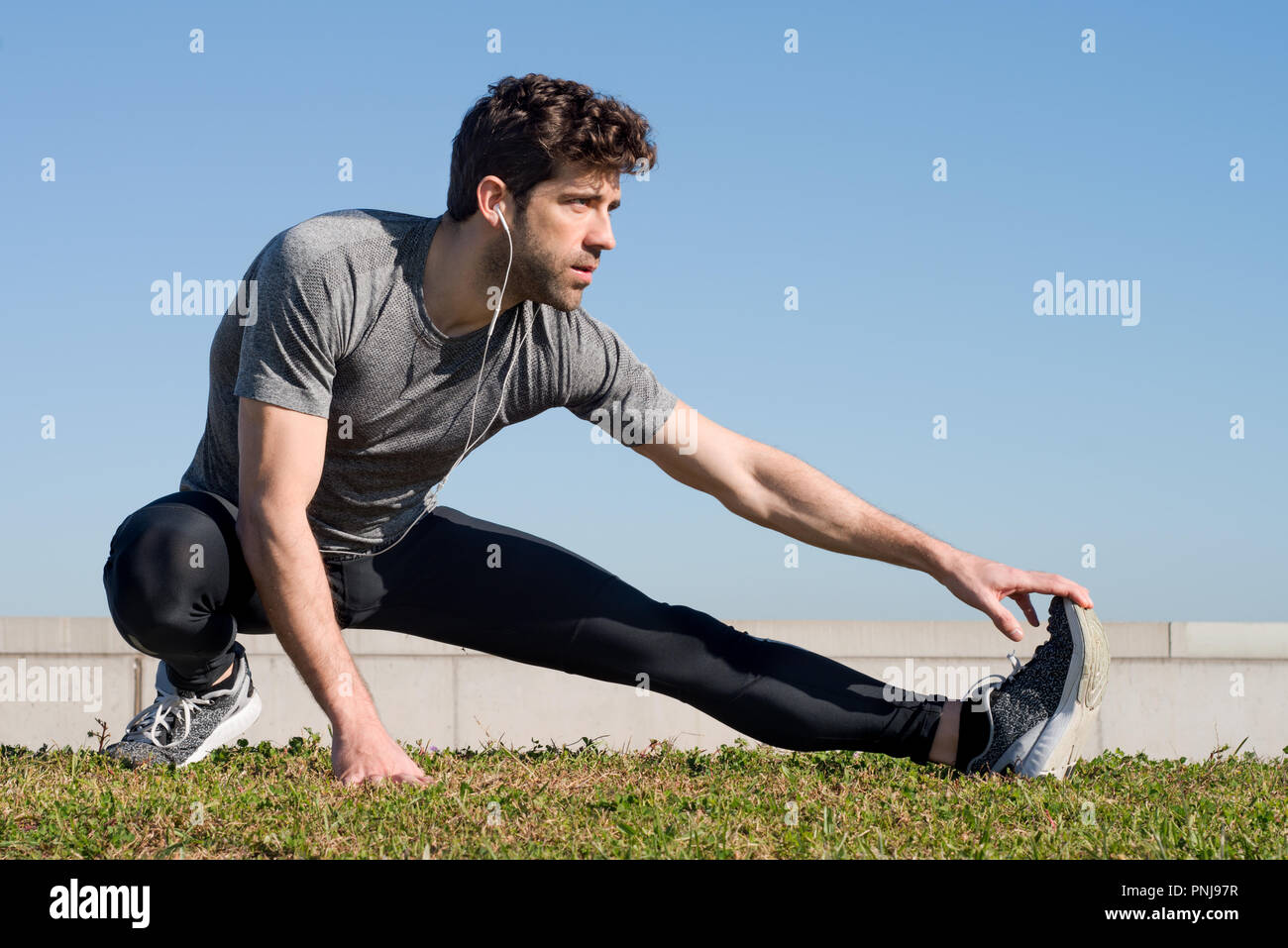 The athlete stretching leg in the grass Stock Photo - Alamy