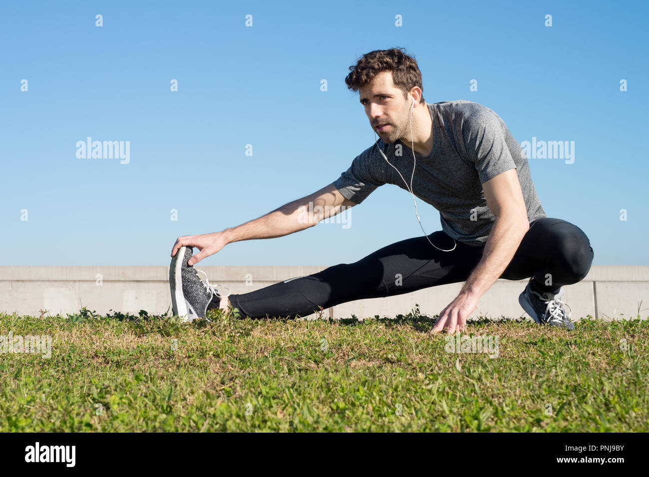 man stretches leg in the ground Stock Photo - Alamy