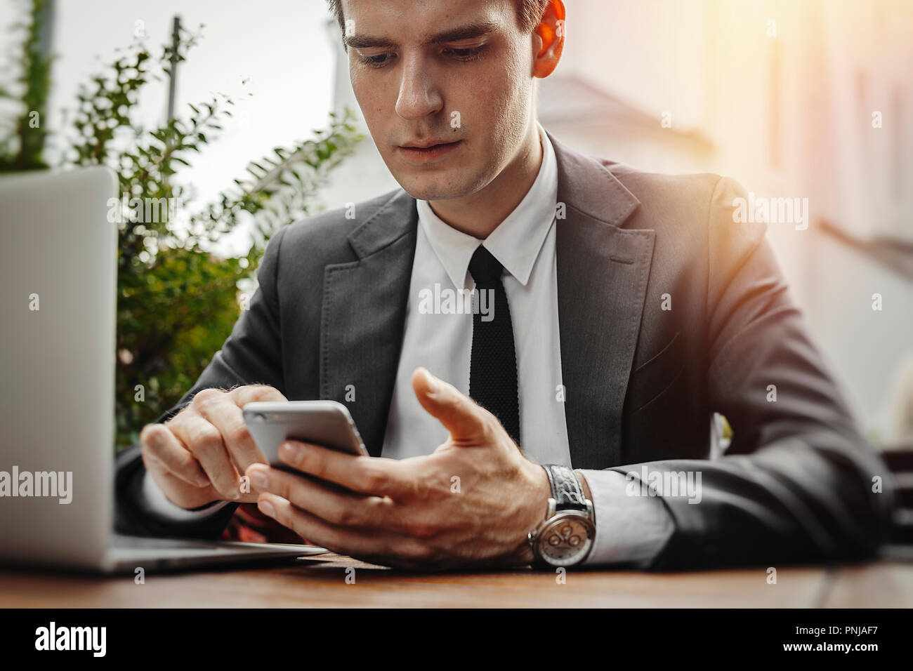 Close up of businessman looking at screen of mobile phone at street ...