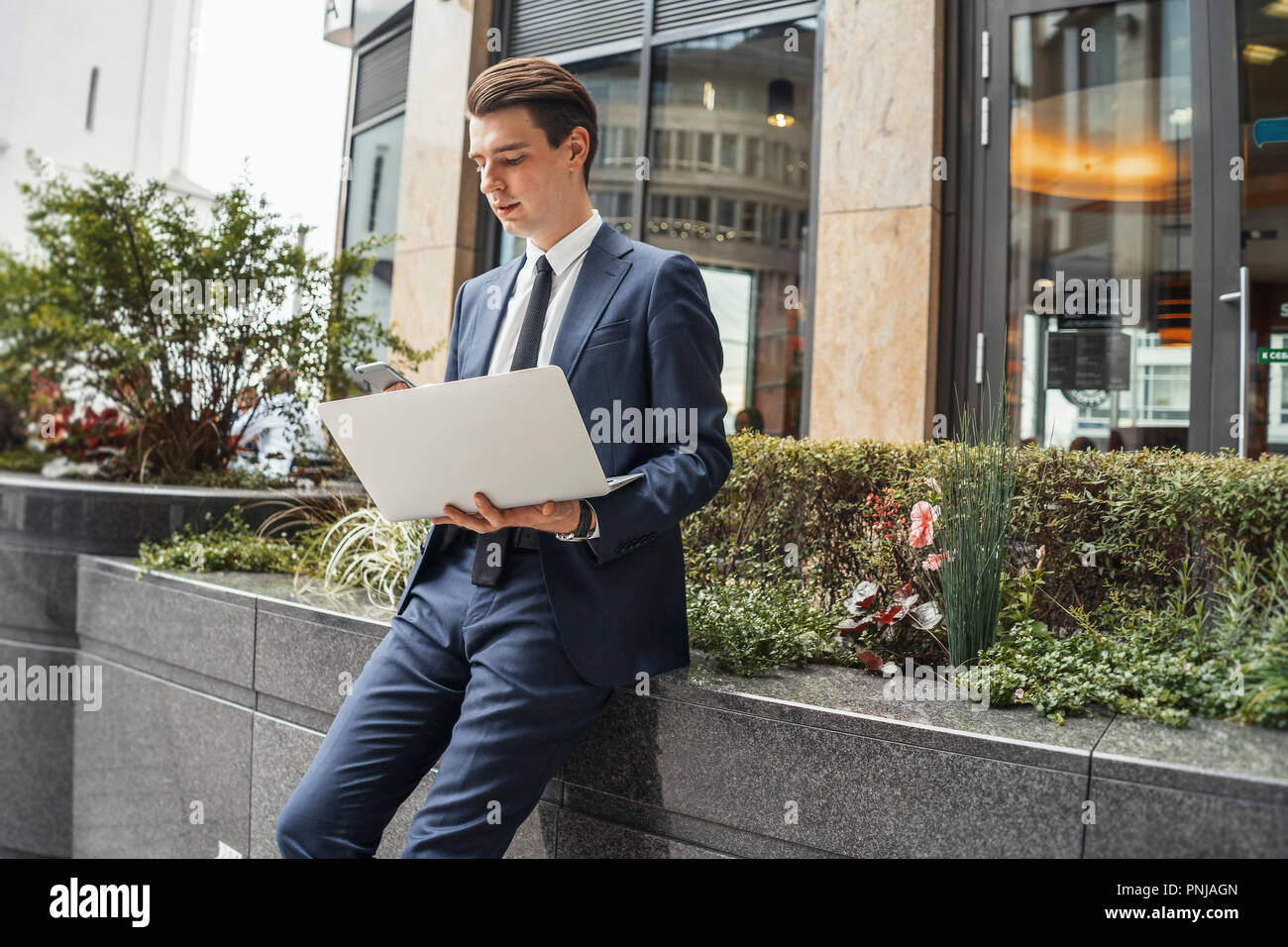 Businessman working on a laptop next to business center at downtown ...