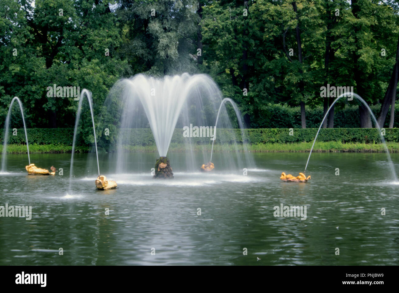 Beautiful fan-shaped fountain in the middle of old pond in the park ...