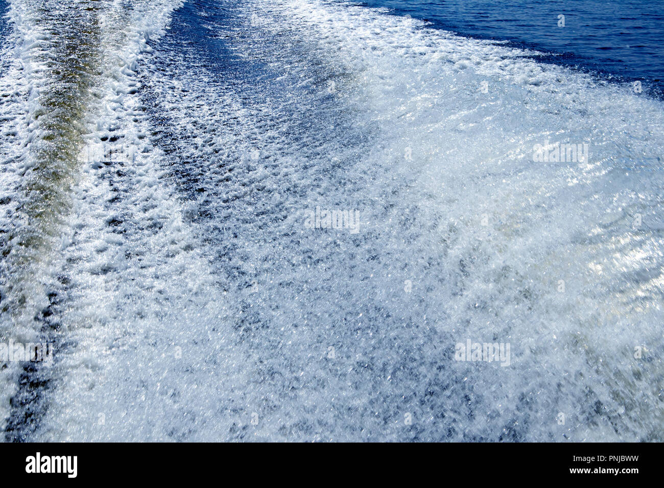 Large boat trail with foamy waves and sprays behind the fast motor boat ...