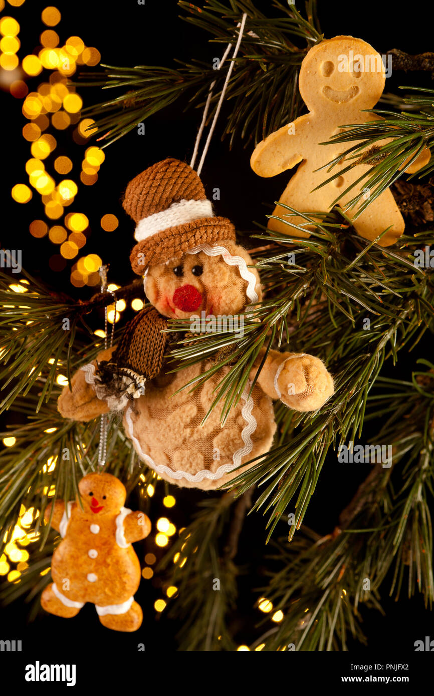 Three gingerbread men hanging in a christmas tree, two fake and one ...