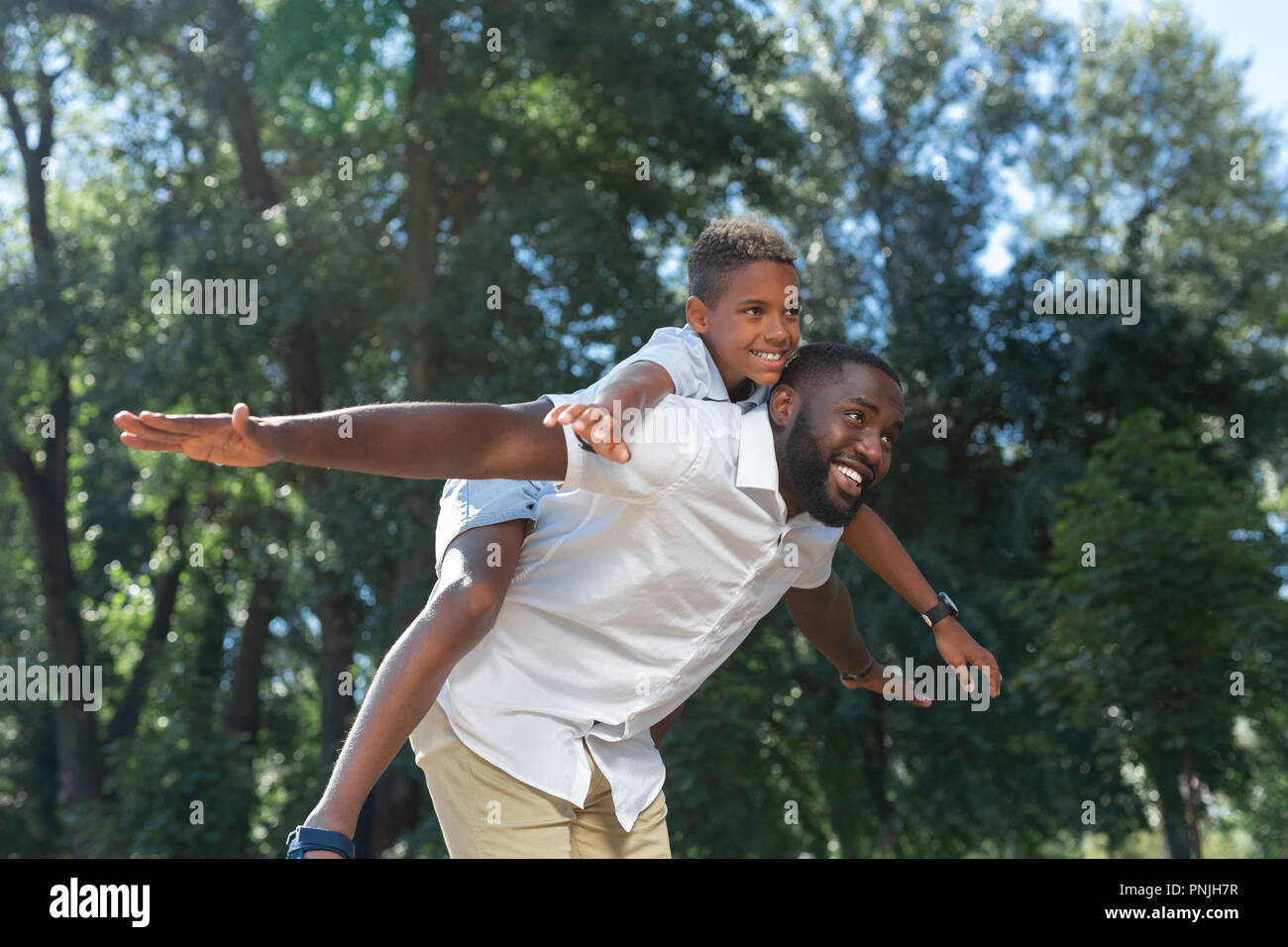 Positive joyful father and son playing together Stock Photo - Alamy