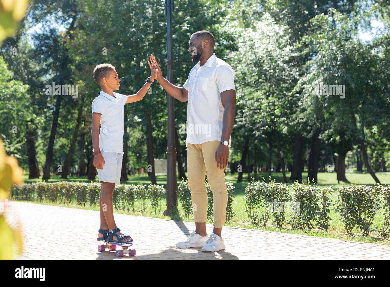 Joyful positive father and son giving high five Stock Photo - Alamy