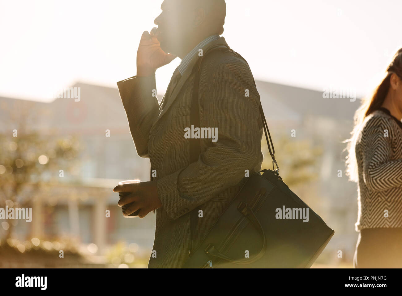 Businessman commuting to office talking over mobile phone with a coffee ...