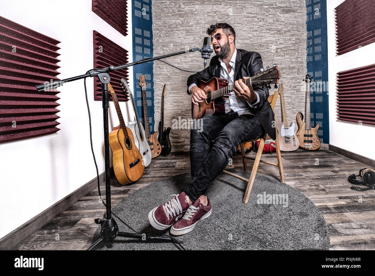 musician singing in front of a microphone with a guitar in a music ...