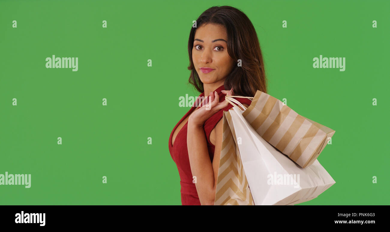 Female Latina shopper holding shopping bags over her shoulder on green ...