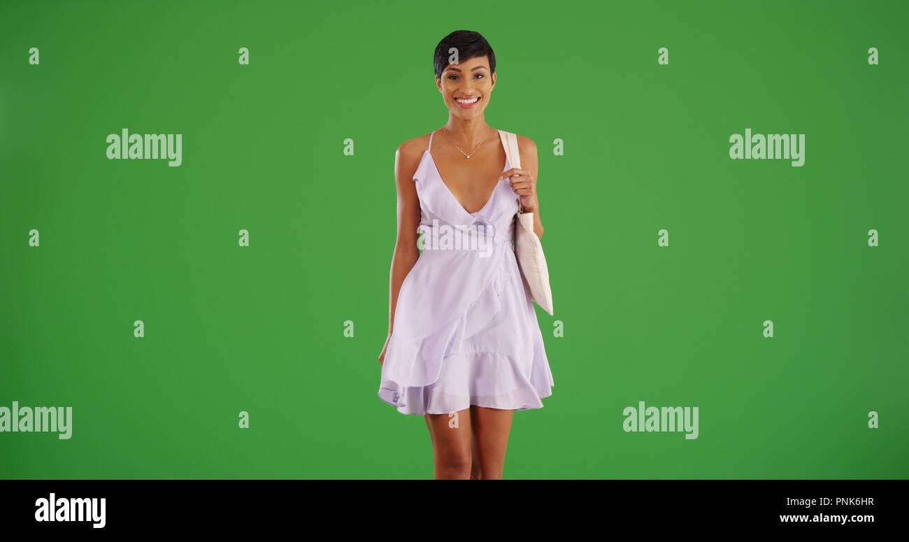 Pretty African-American female wearing dress smiling at camera on green ...
