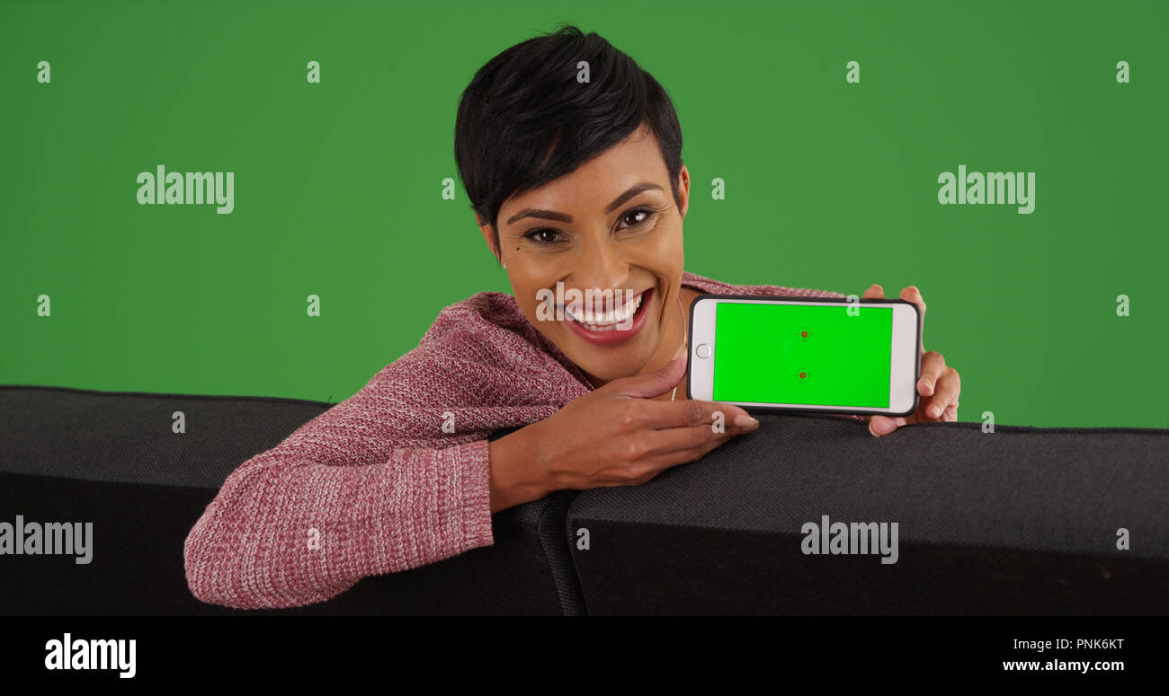 Lovely black woman showing phone with green screen on display on green ...