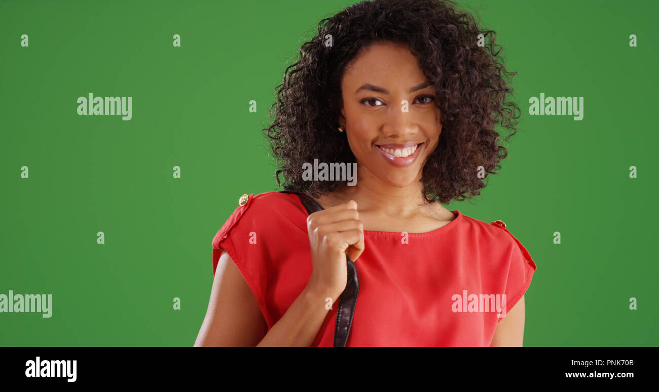 Happy African American woman with purse smiling at camera on green ...