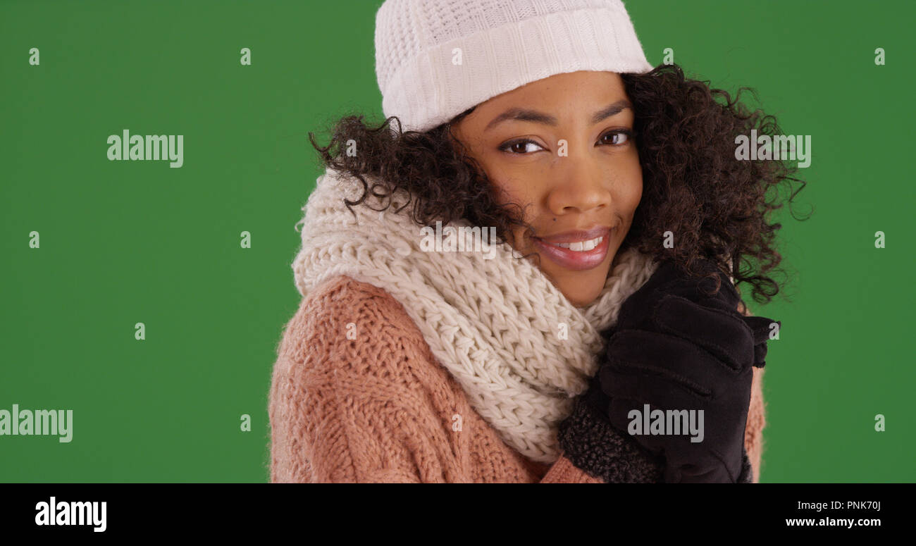 Cold African American girl in winter attire looking at camera on green ...