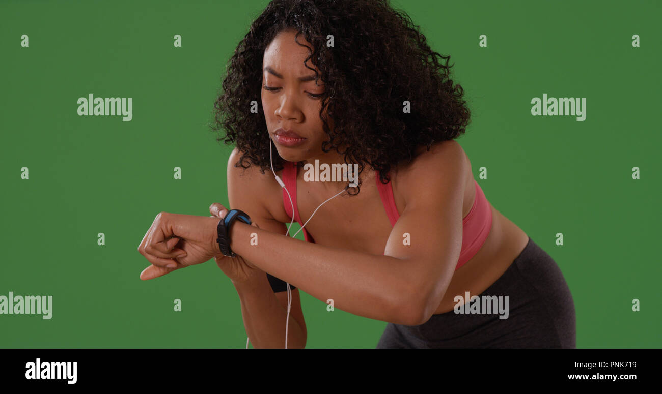 Athletic black female runner checking timer on watch on green screen ...