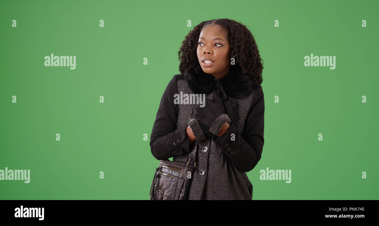 Young black female wearing coat and gloves shivering on green screen ...