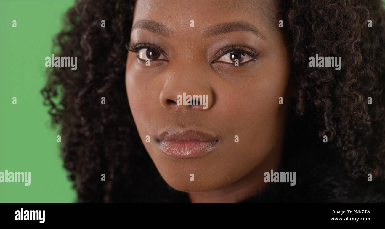 Close up portrait of African American woman gazing at camera on green ...
