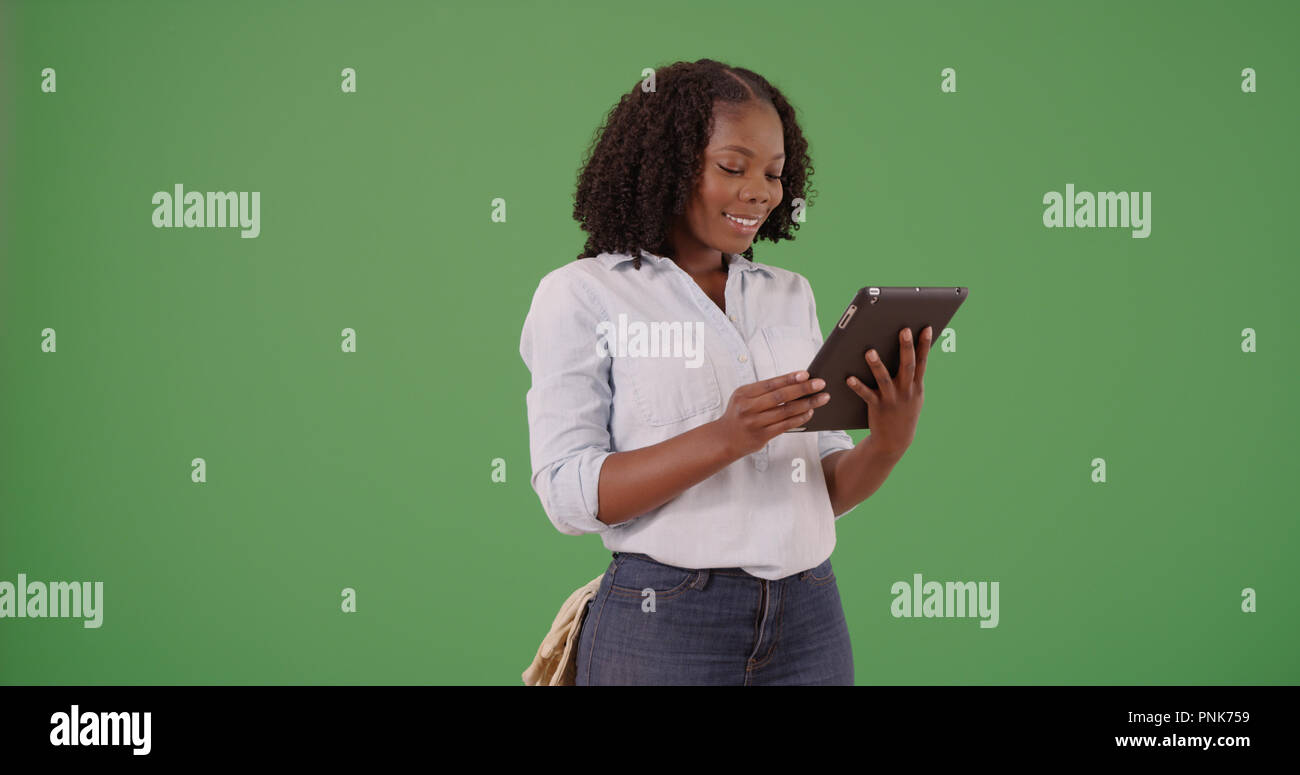 Smiling African American woman using tablet device on green screen ...