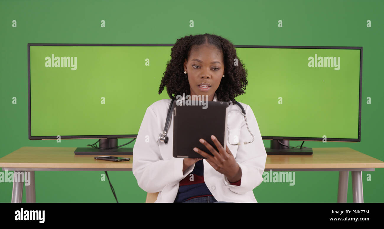 Black female doctor using tablet near computers with green screen ...