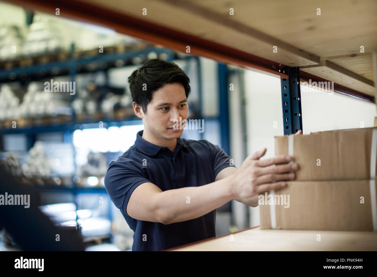 Male picking up box from shelf in distribution warehouse Stock Photo ...