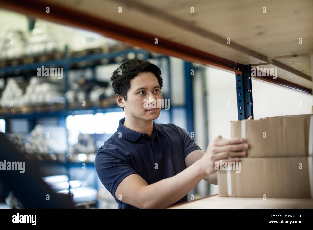 Male picking up box from shelf in distribution warehouse Stock Photo ...