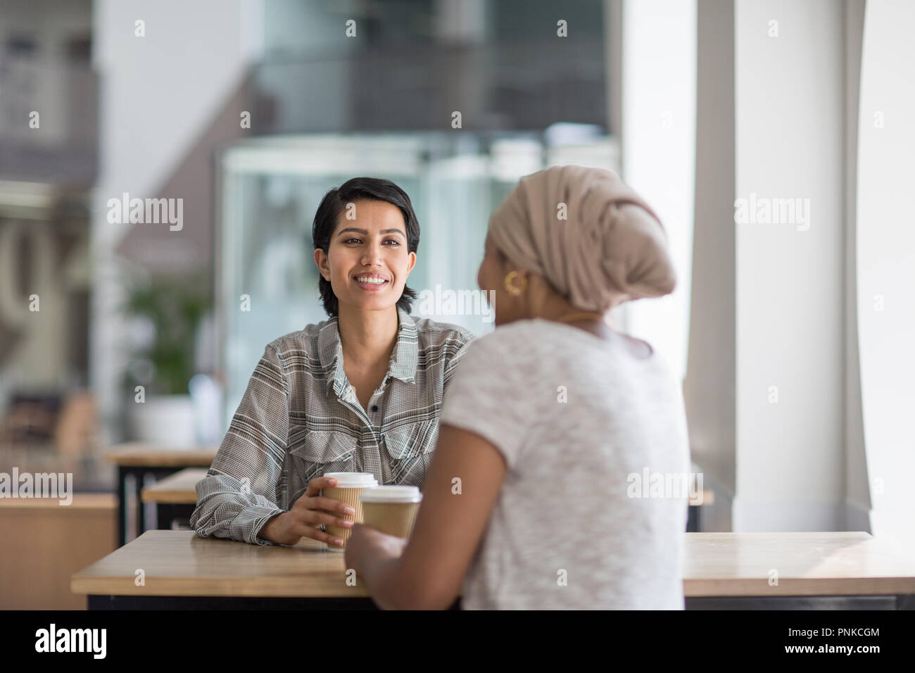 Female Muslim co-workers having coffee together Stock Photo - Alamy
