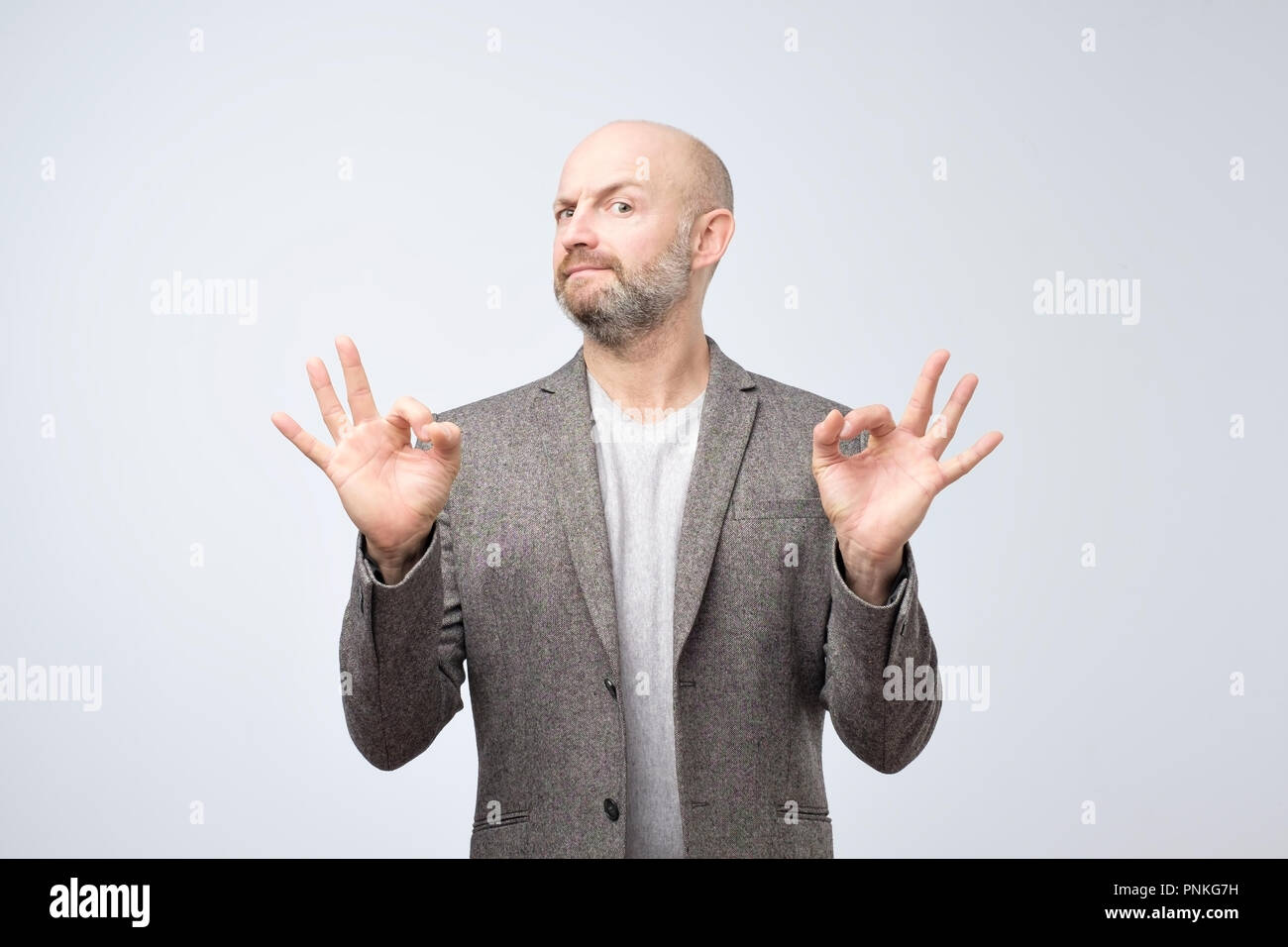 A handsome man in suit isolated on gray background showing ok sign ...