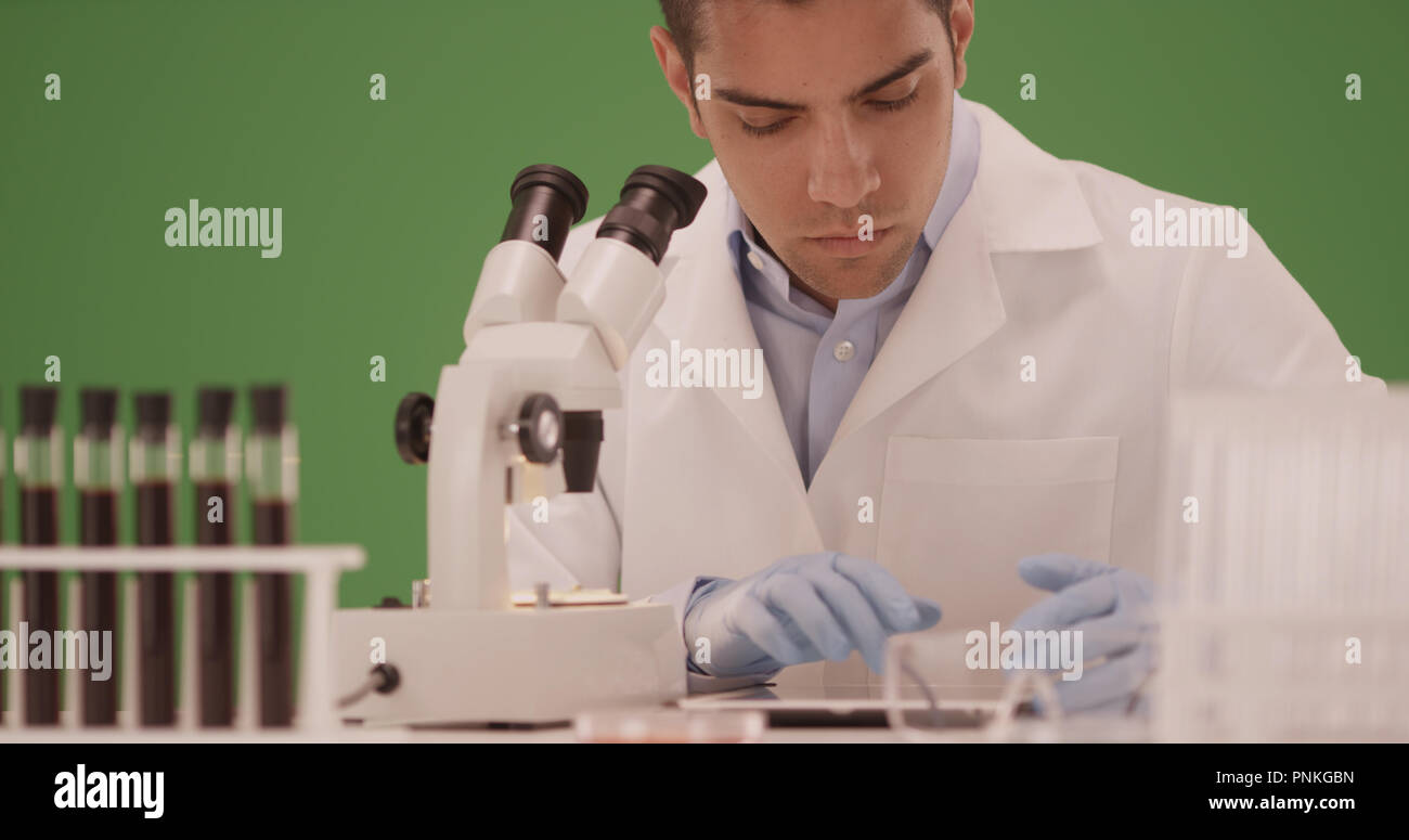 Millennial Hispanic medical scientist working in his lab on green ...