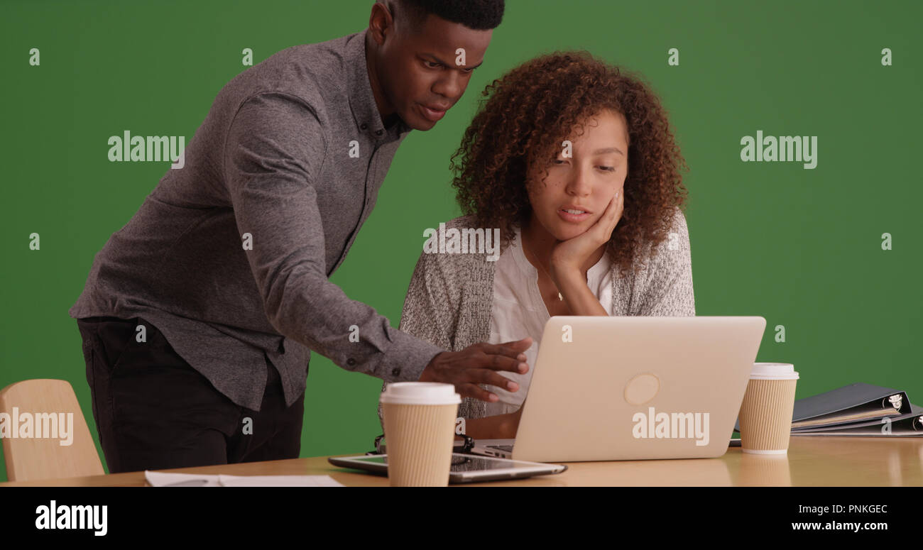 Office manager instructing employee working on laptop on green screen ...
