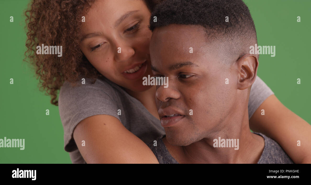 Close up portrait of Black man and woman embracing each other on green ...