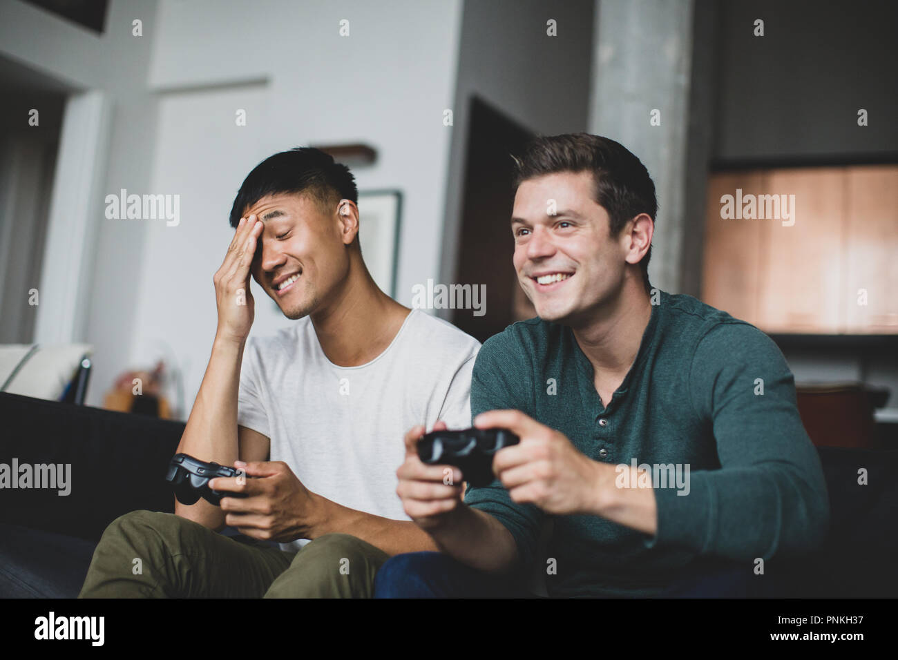 Male friends playing on a games console Stock Photo - Alamy