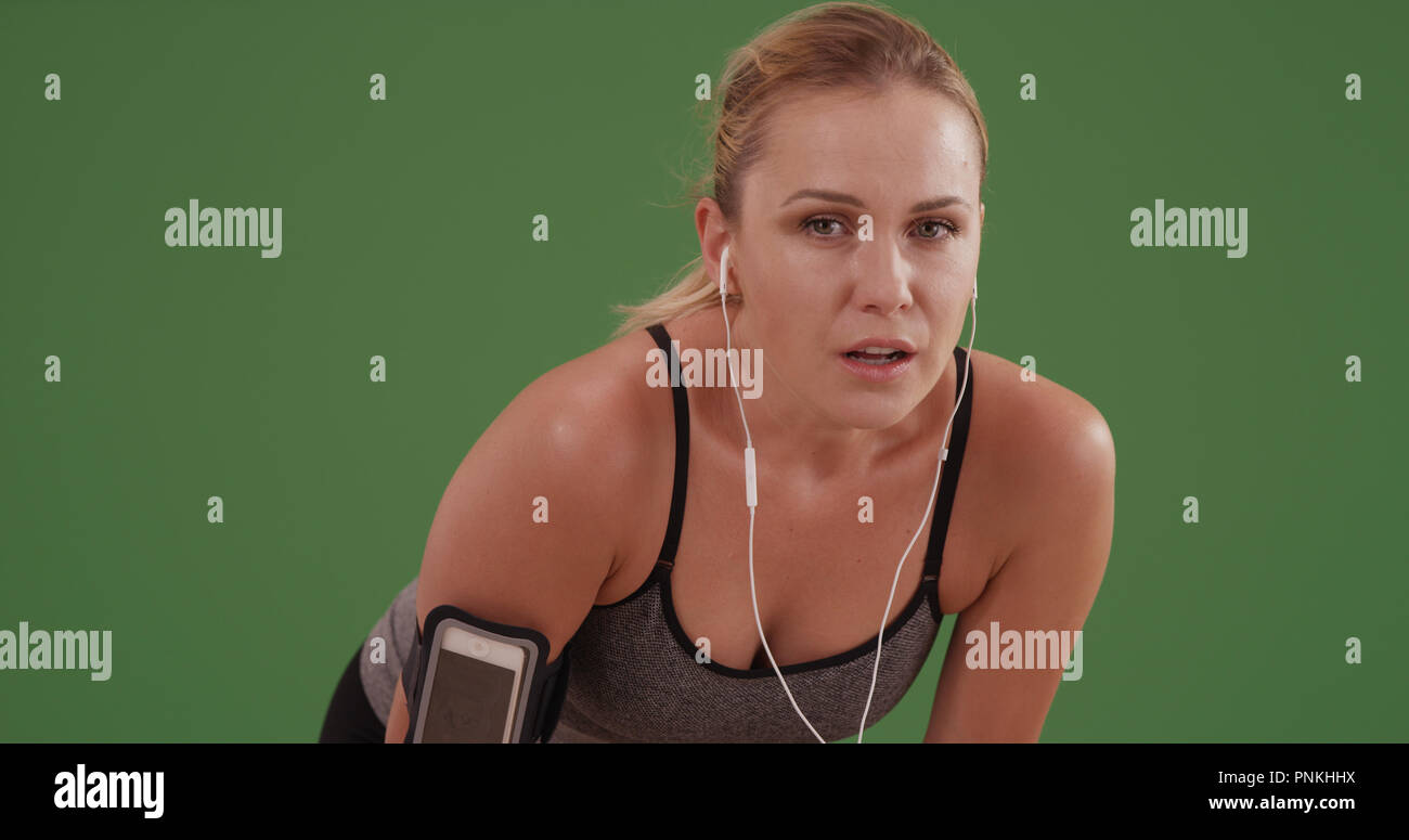 Woman runner looking at camera on green screen Stock Photo - Alamy