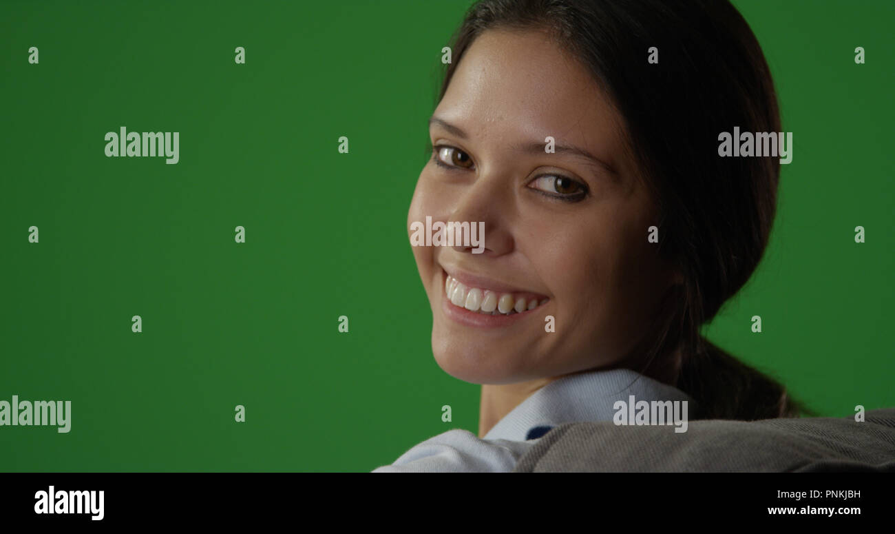 Pretty brunette woman looking back and smiling at camera on greenscreen ...
