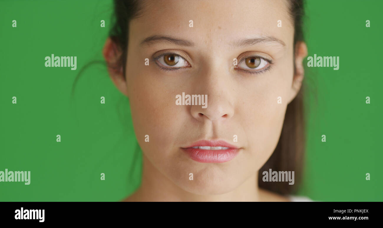 Close-up of serious looking millennial girl's face on green screen ...