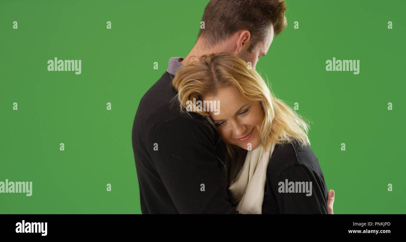 Sweet modern couple hugging each other tenderly on green screen Stock ...
