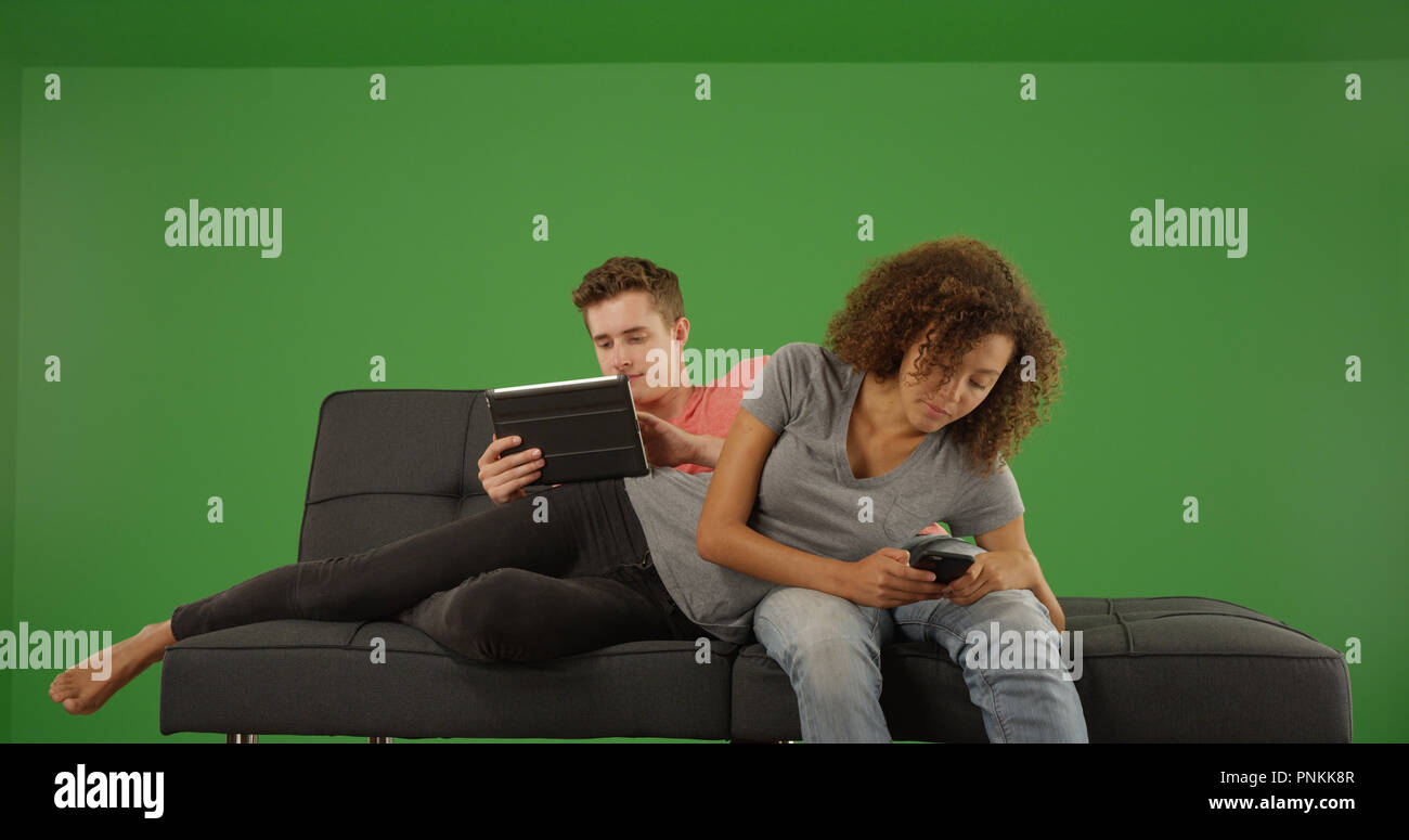 Bored couple using handheld tech devices on couch on green screen Stock ...