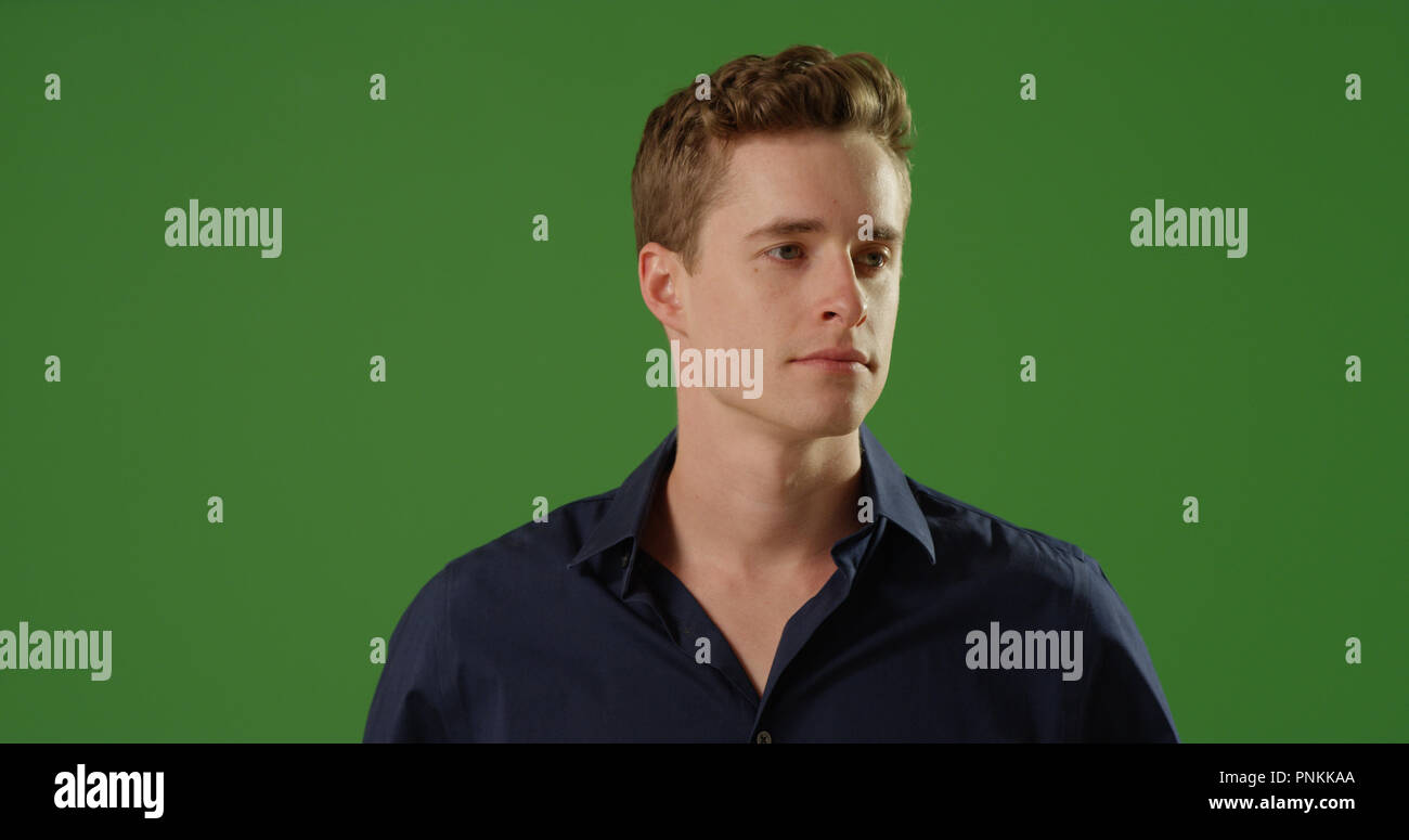 Handsome white male standing looking off screen in a button up on green ...
