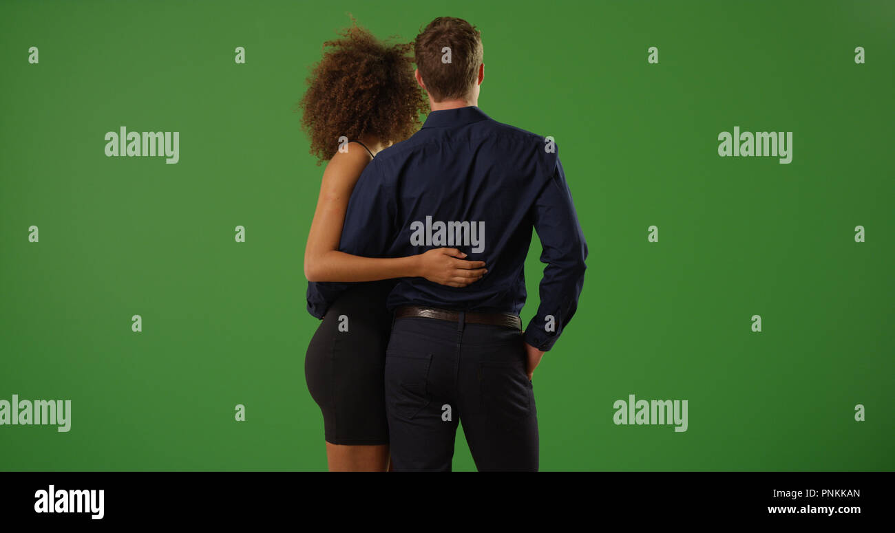 Rear view of young couple out on date holding each other on green ...