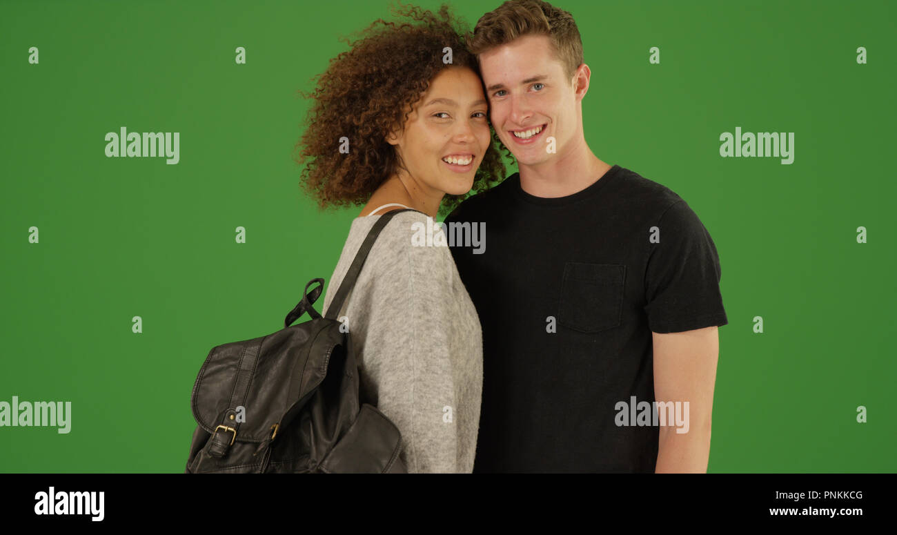 Happy Millennial couple standing together smiling at camera on green ...