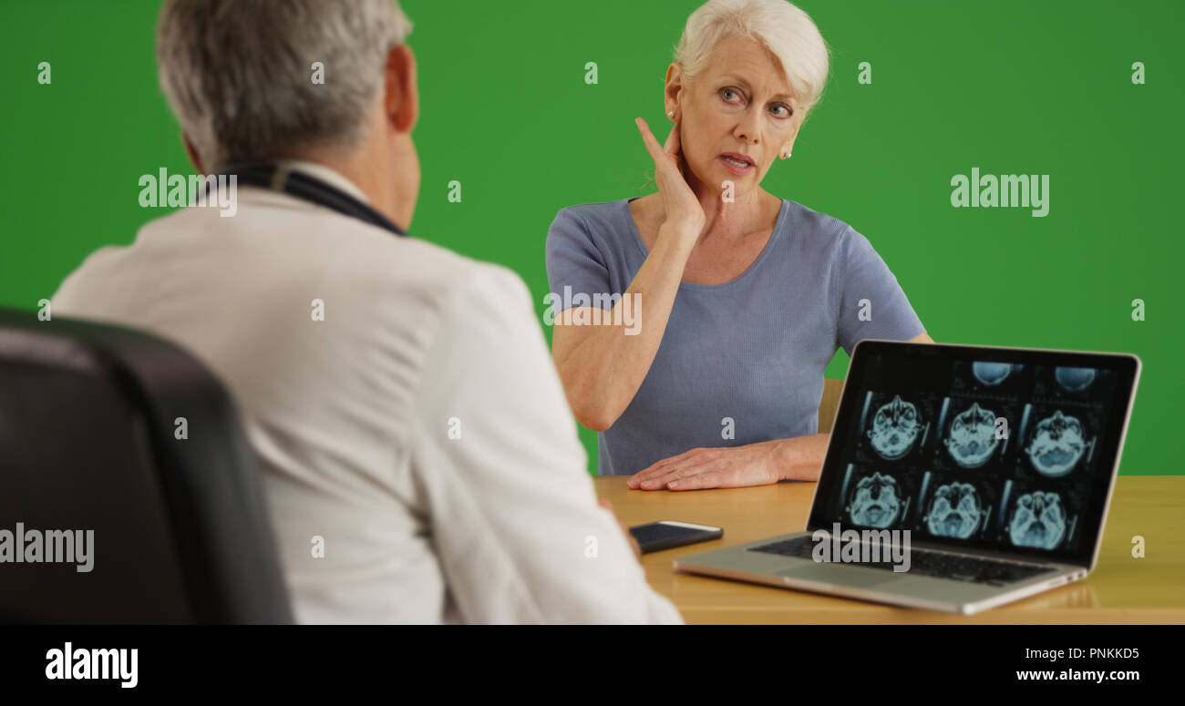 Woman patient telling her doctor about the pain in her neck on green ...