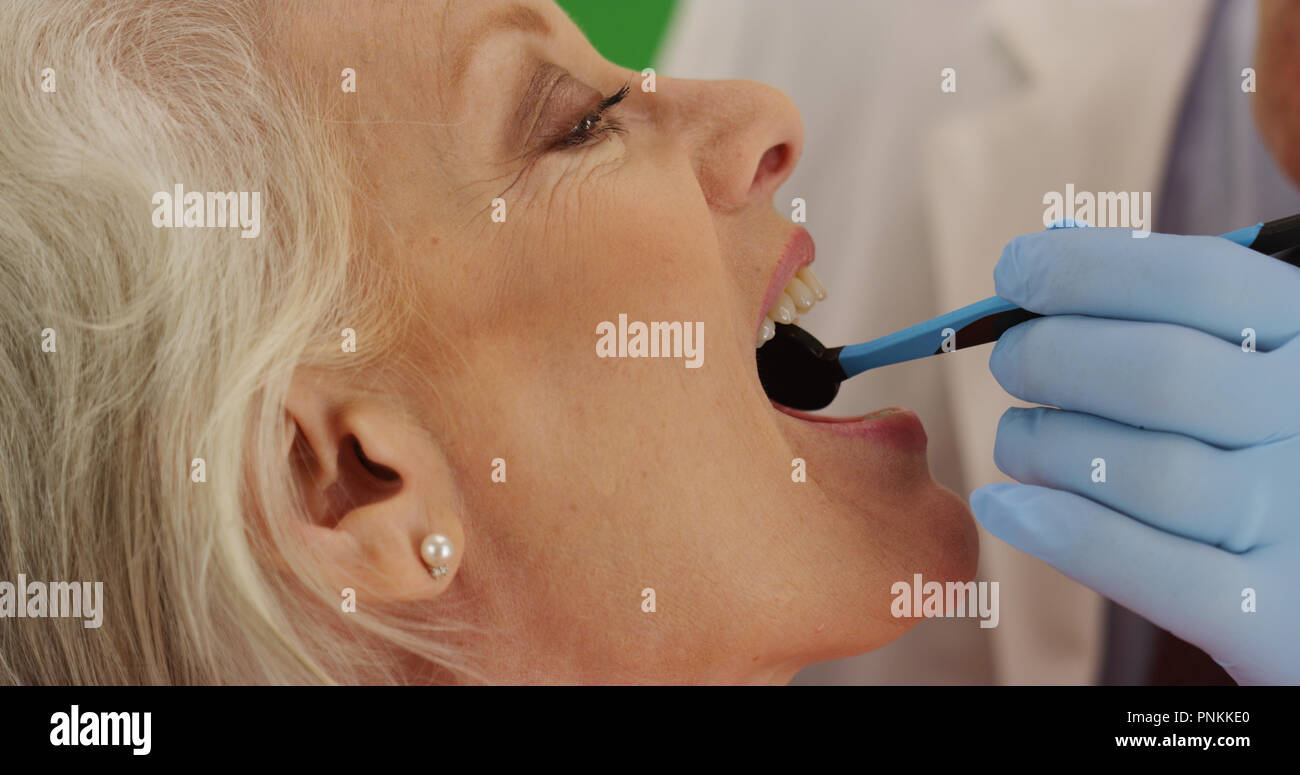 Dentist examining elderly woman's teeth during checkup on green screen ...