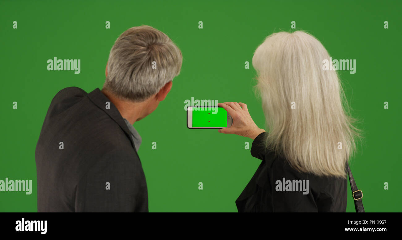 Senior couple taking photo with smartphone camera on green screen Stock ...