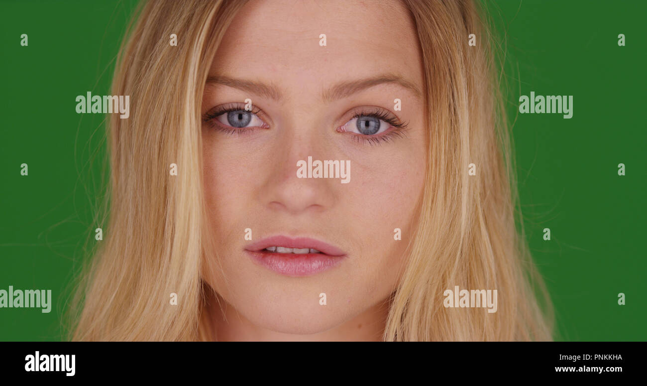 Close up portrait of beautiful millennial blonde woman on green screen ...