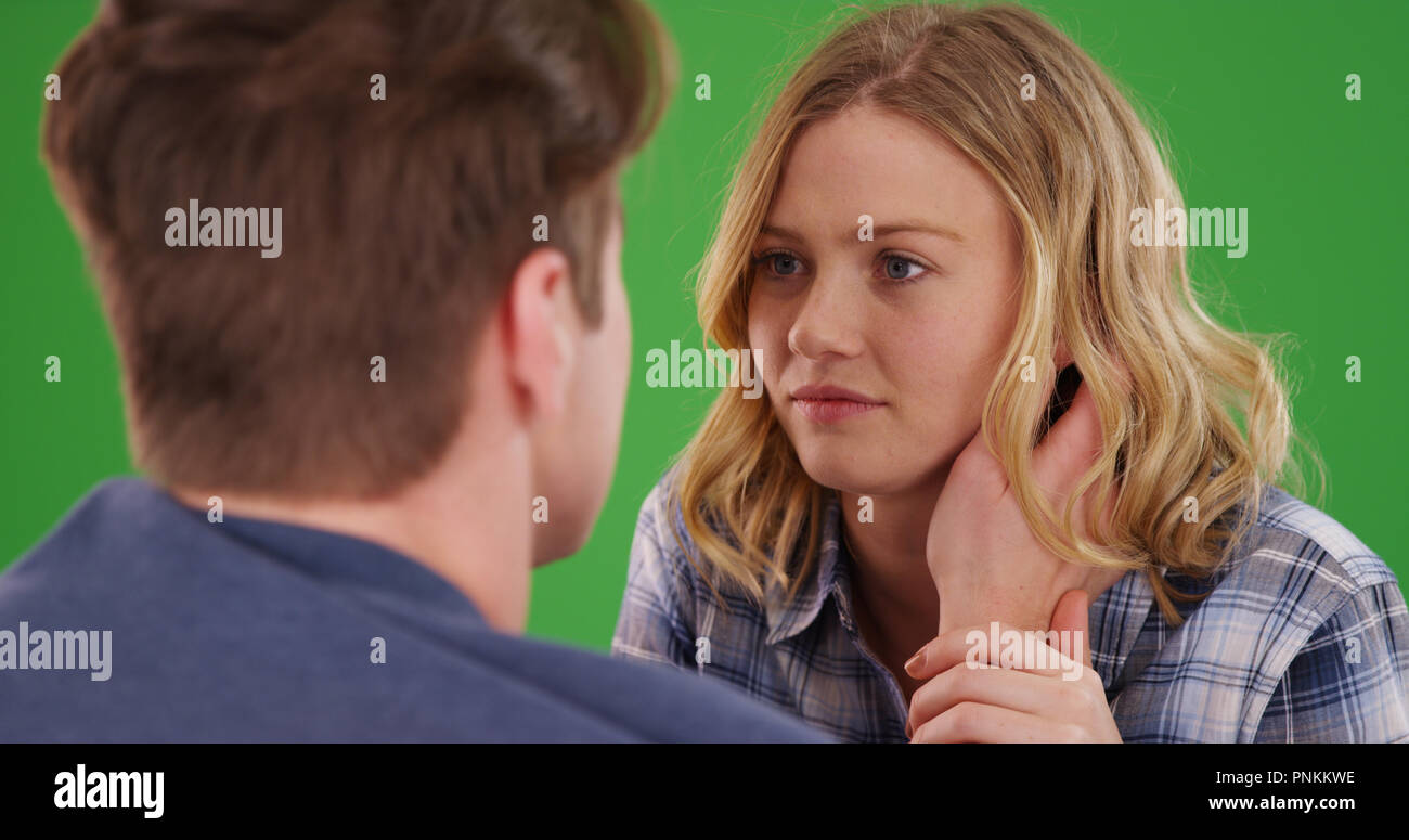 Over the shoulder shot of male showing affection to girlfriend on green ...