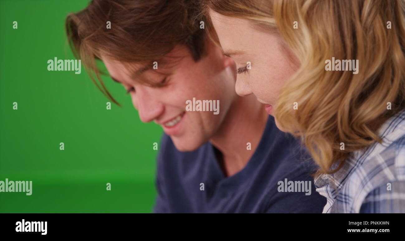 Closeup of male and female looking down at tablet or laptop on green ...
