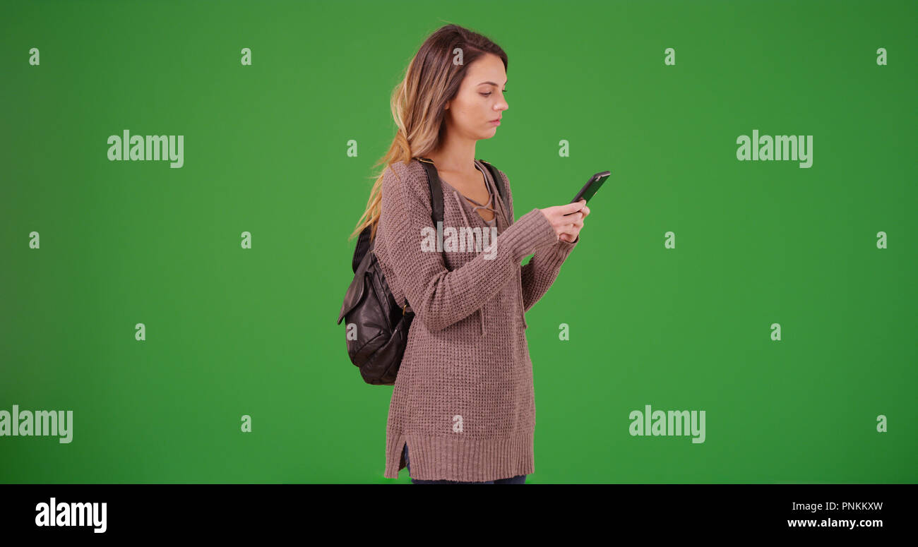 Caucasian millennial girl responding to text on phone on green screen ...