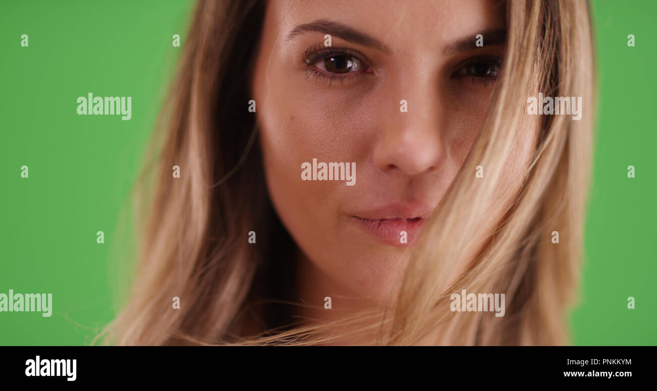 Closeup of attractive millennial girl staring at camera on green screen ...