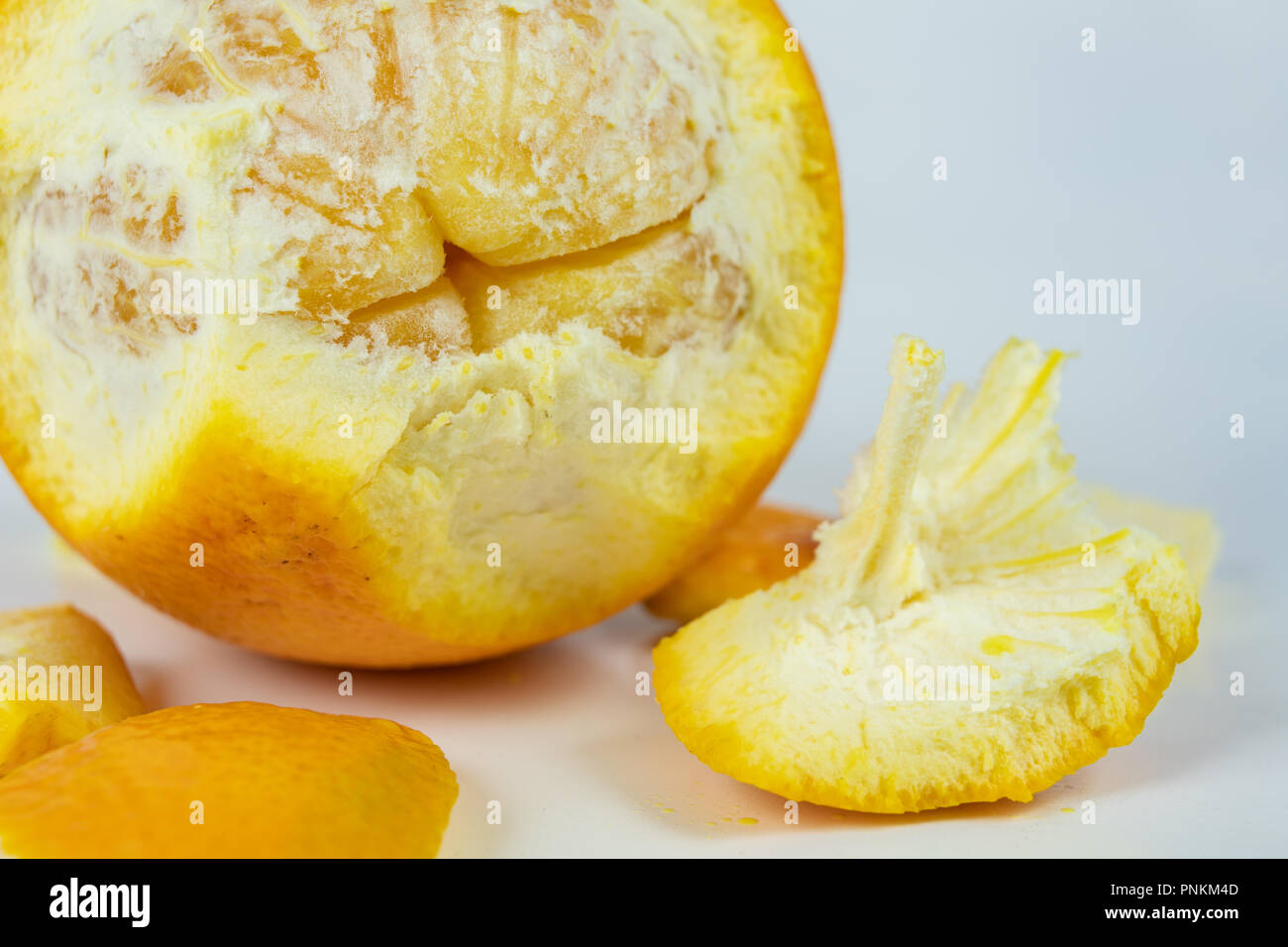 Peeled orange with very thick skin on a white kitchen table. Citruses ...
