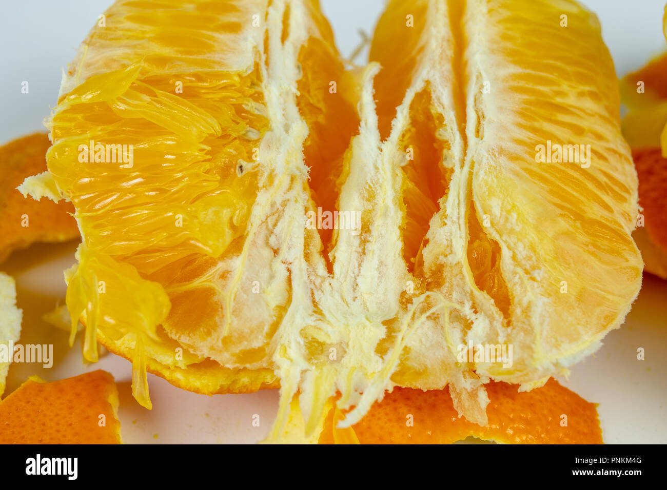 Peeled orange with very thick skin on a white kitchen table. Citruses ...