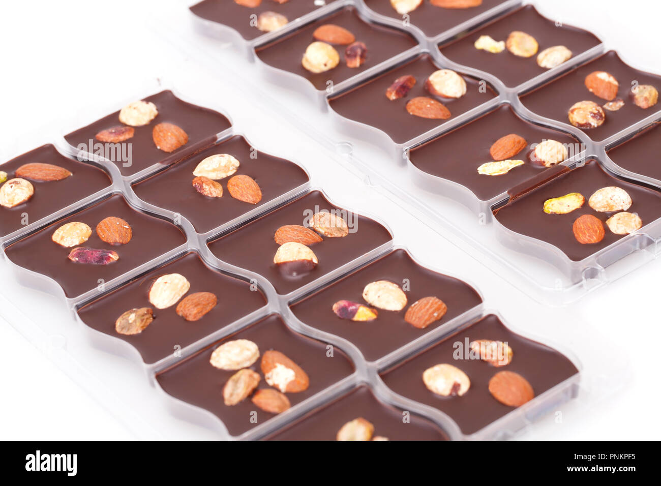 Chocolate with assortment nuts in plastic boxes on white background ...